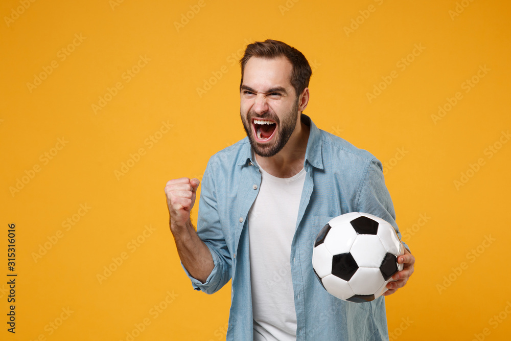 Joyful happy young man in blue shirt posing isolated on yellow orange ...