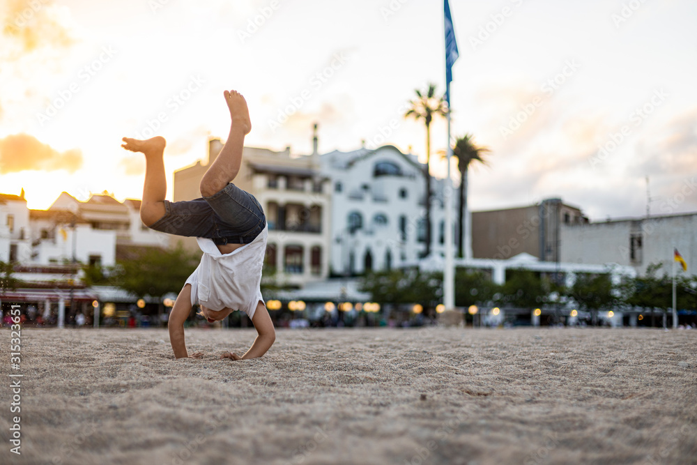 Little child making a somersault on the beach Stock Photo | Adobe Stock
