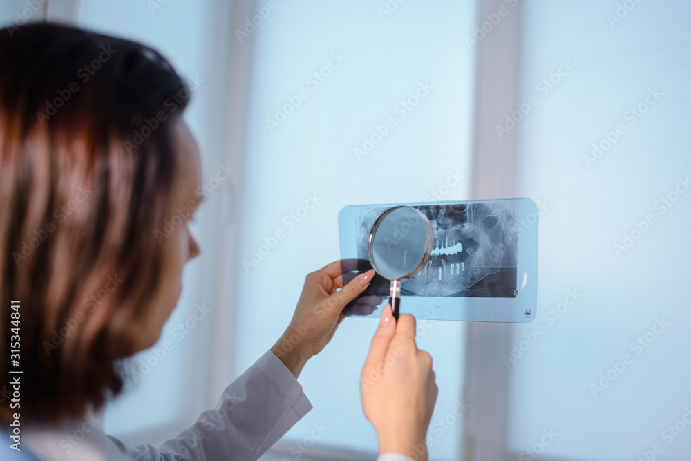 Close up picture of young woman doctor dentist who analysis dental x ...