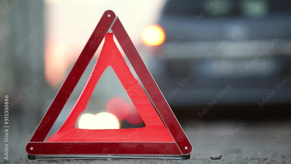 Red emergency stop sign behind broken blurred car with blinking lights ...
