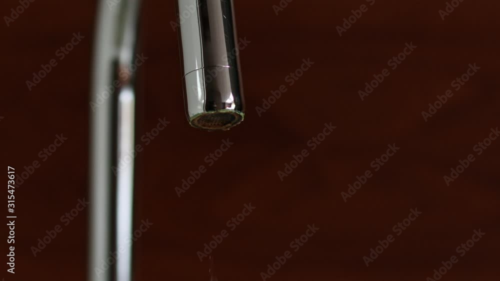Water drips from it drop by drop. Close-up of tap water dripping with ...