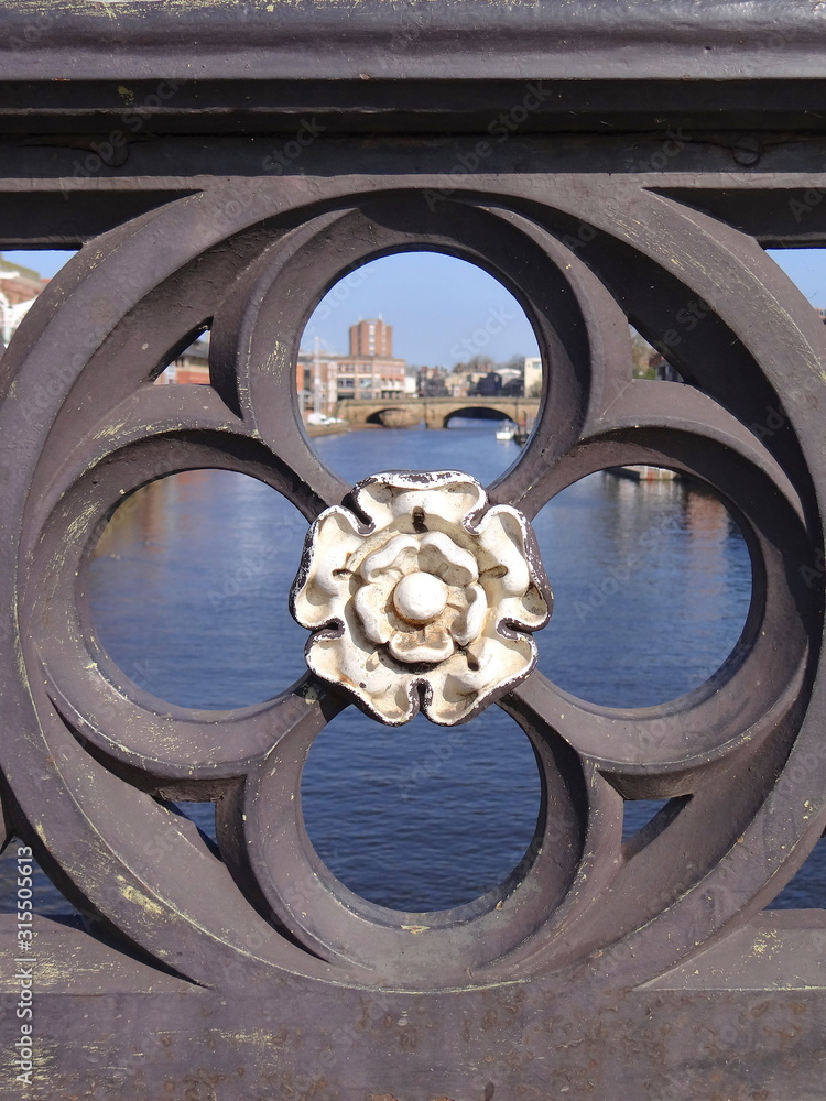 White heraldic Yorkshire rose on Gothic style iron bridge over river ...
