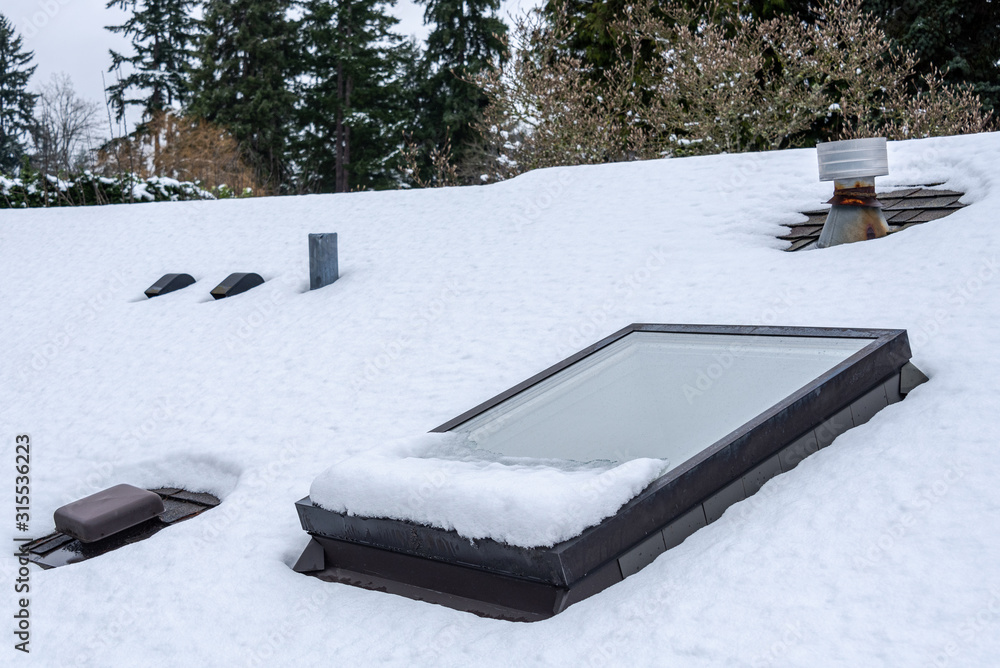 Residential house rooftop covered in fresh snow, skylight, roof vents ...