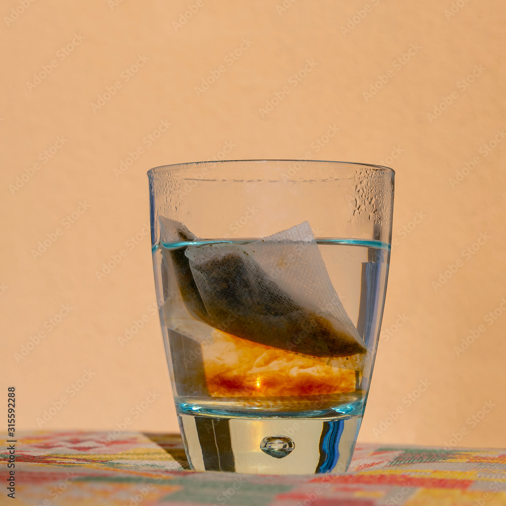 An infusion tea bag inside a transparent glass of hot water releases ...