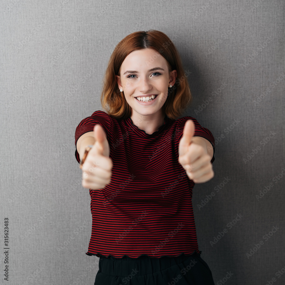 Happy vivacious young woman giving a thumbs up Stock Photo | Adobe Stock