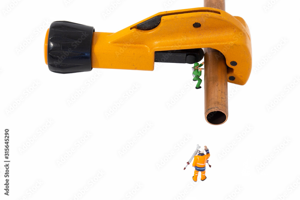 Miniature scale model construction workers with a copper pipe and a ...