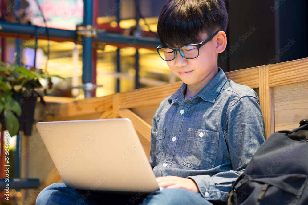 Smart asian preteen boy using computer laptop studying online lessons ...