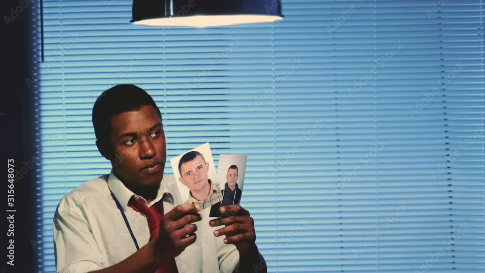 Vídeo do Stock: Close-up of mixed-race young detective showing photos ...