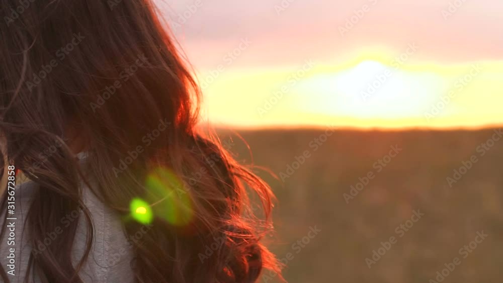 Close-up of a girl with long flowing hair standing in the sunset sun in ...