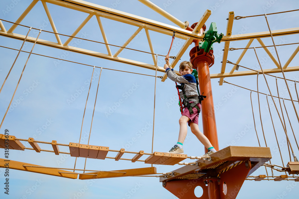 Happy little kid boy climbing on high rope course trail. Active child ...
