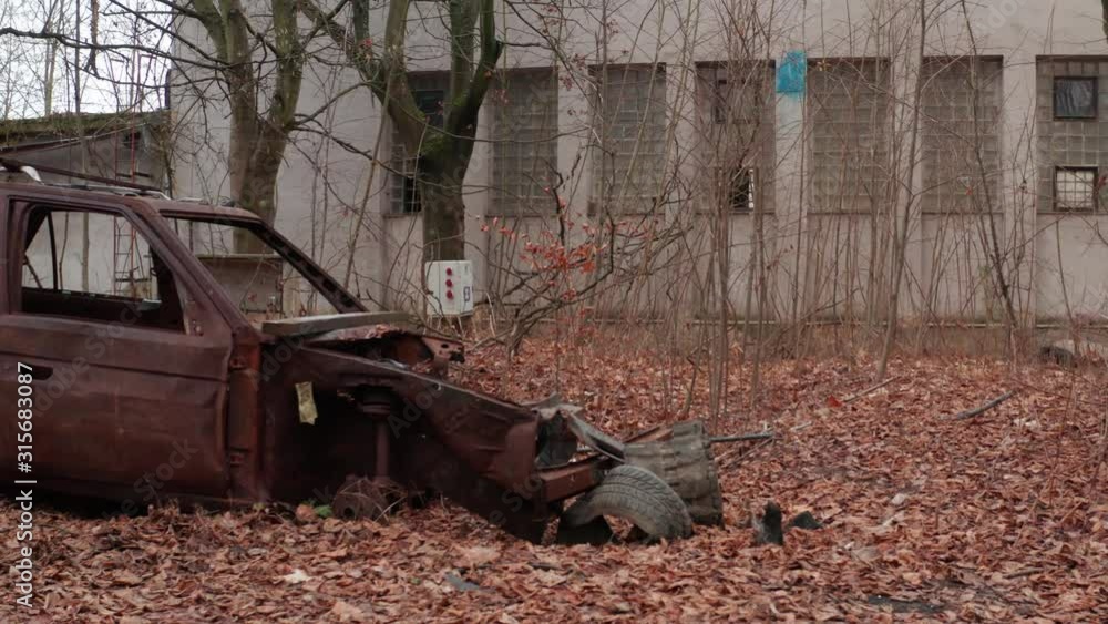 Rusty car wreckage in front of an old shabby rundown building Stock ...