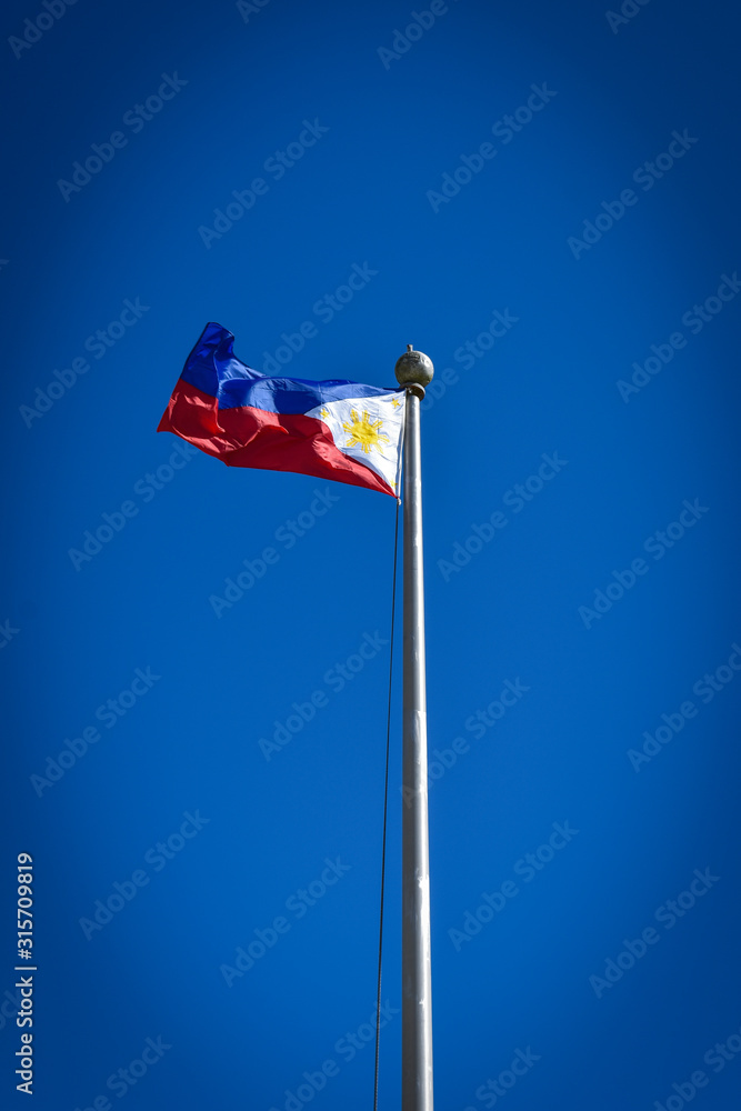 Philippine national flag waving against a clear, blue sky with the blue ...