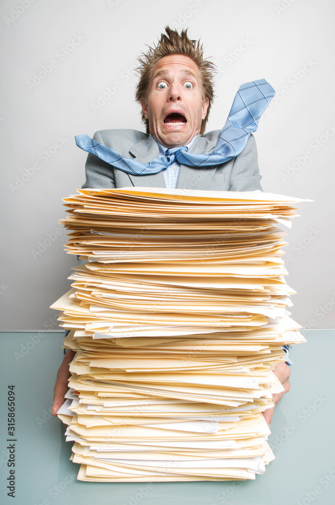 Shocked businessman crying for help from behind the giant pile of ...