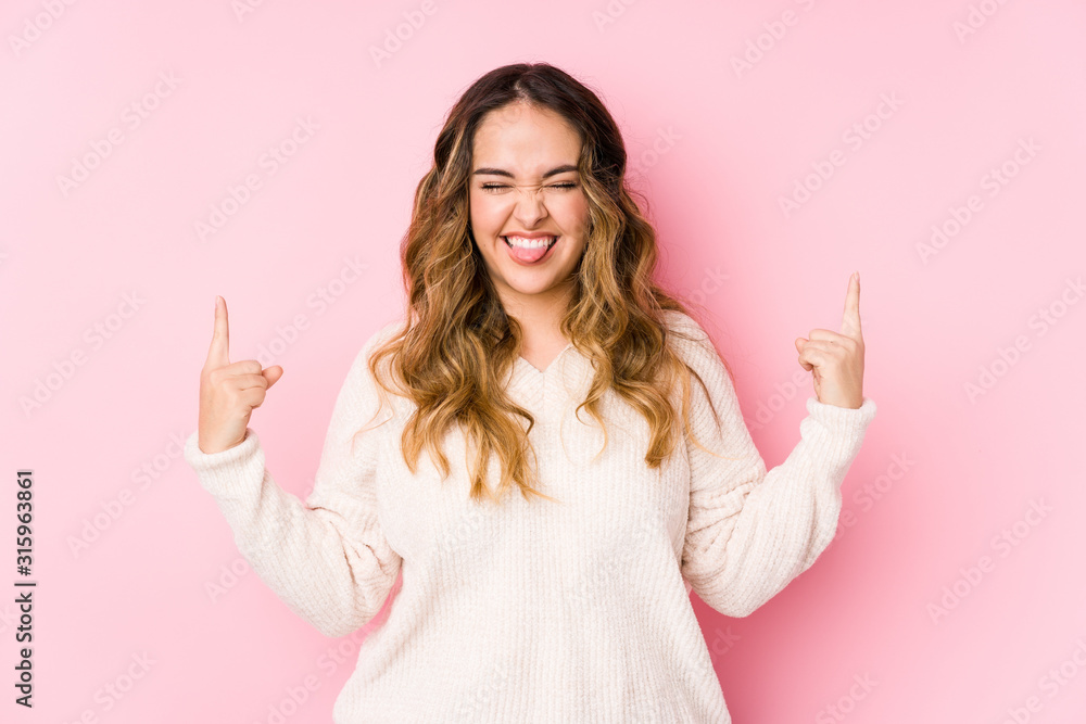 Young curvy woman posing in a pink background isolated showing rock ...