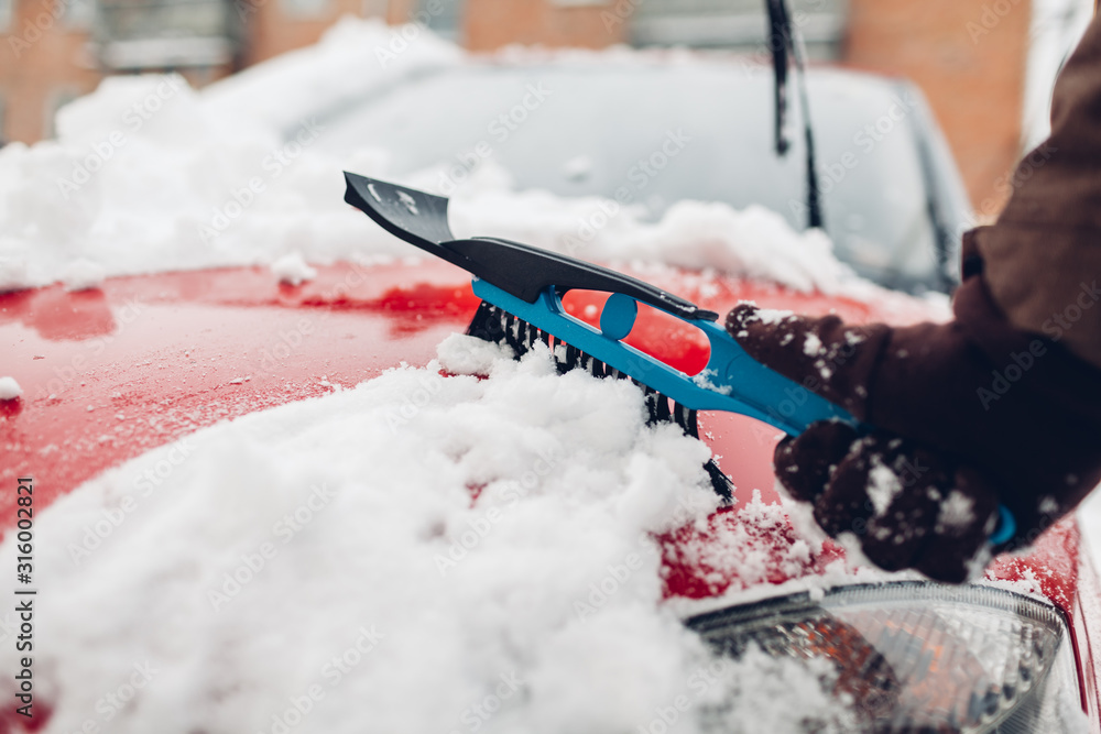 Car cleaning from snow using broom. Man taking care of automobile ...