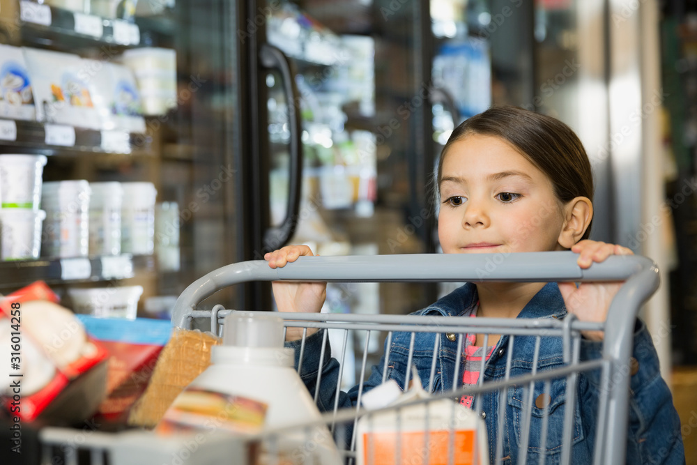 Girl pushing shopping cart in market Stock Photo | Adobe Stock
