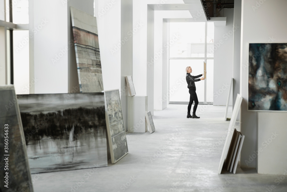 Art dealer examining painting in art gallery Stock Photo | Adobe Stock