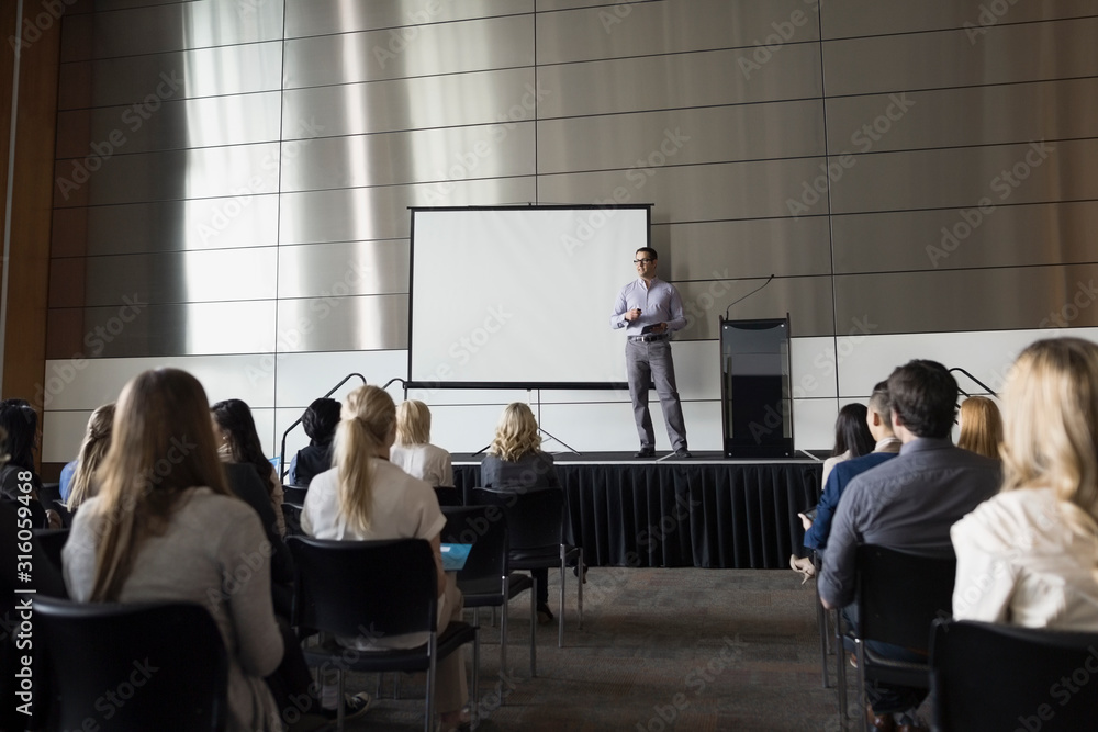 Professor on stage speaking to students in auditorium Stock Photo ...