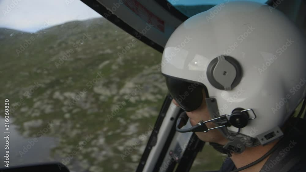 Inside cockpit of helicopter in flight with pilot and left pan to ...