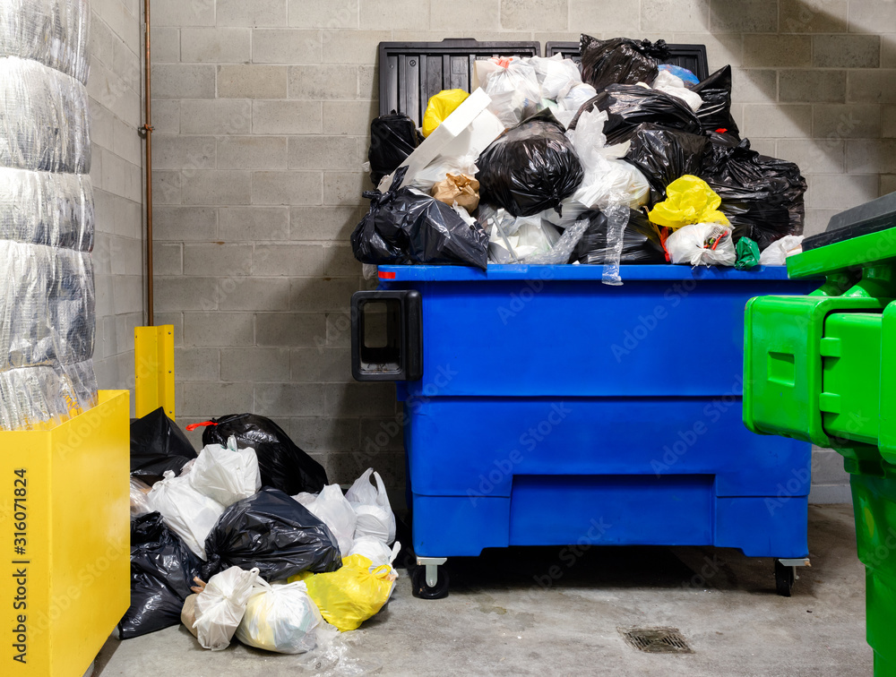 Overloaded household garbage container in garbage room of residential ...