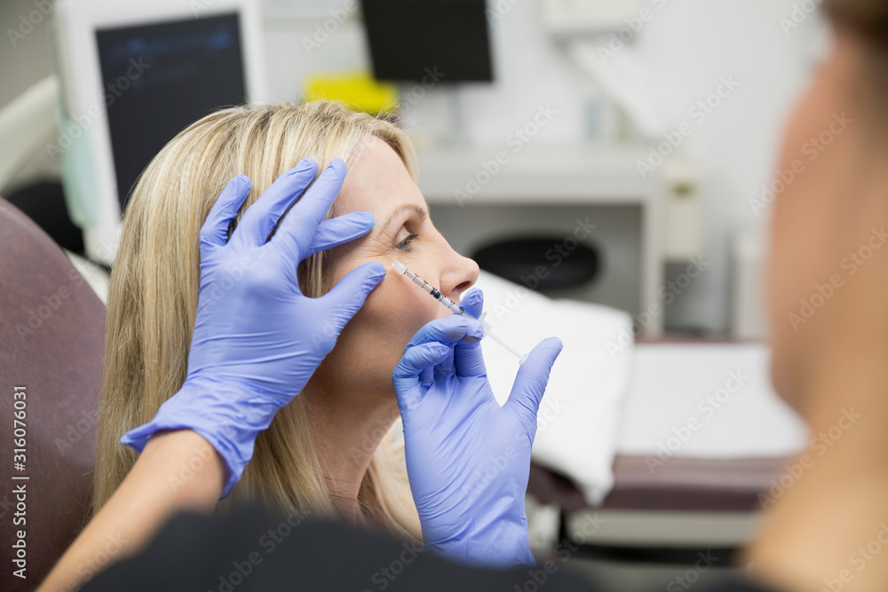 Technician giving woman botox injection corner of eye Stock Photo ...