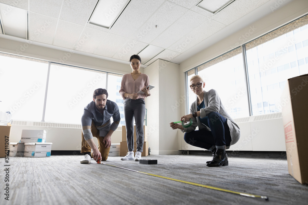 Business people with tape measure measuring floor space in new office ...