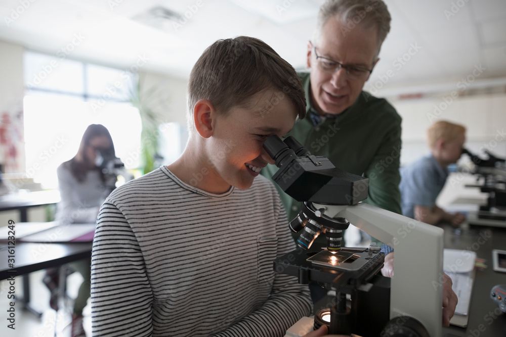 Teacher and middle school student using microscope, conducting ...