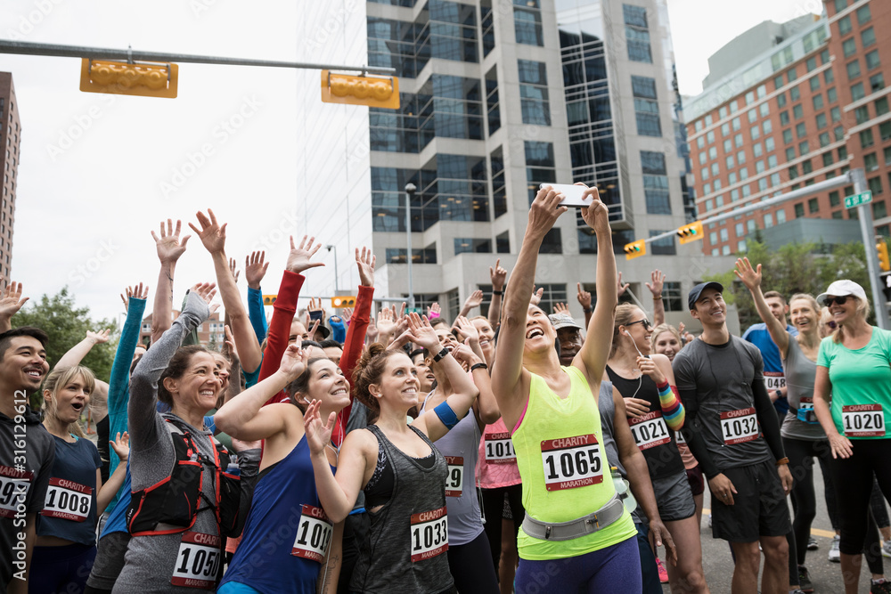 Marathon runners posing, waving and cheering for selfie at starting ...
