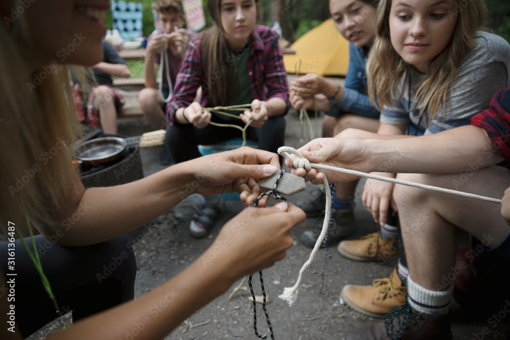 Female teacher teaching teenage outdoor school students how to tie ...