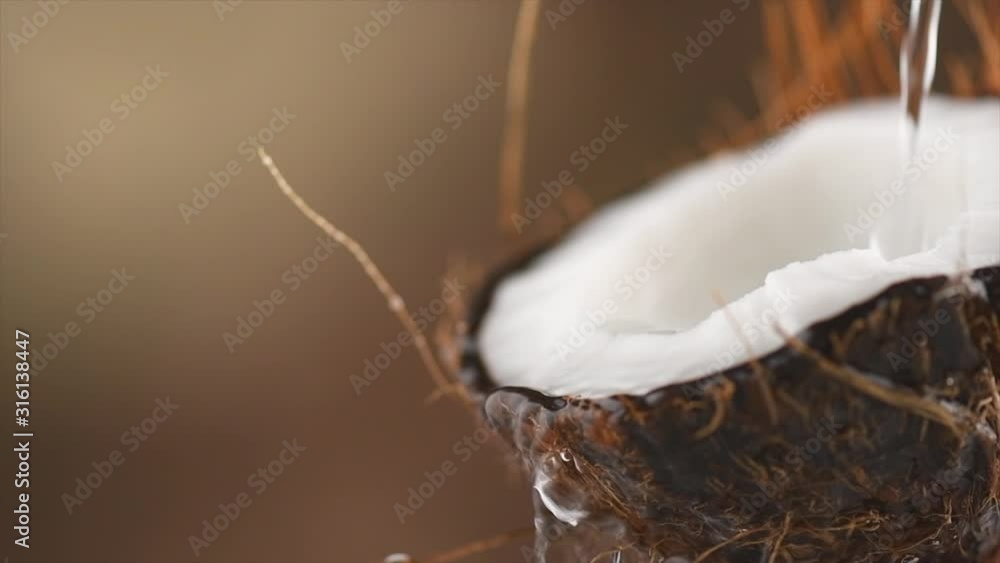Coconut pouring water, dripping coconut milk, drops of coco nuts oil ...