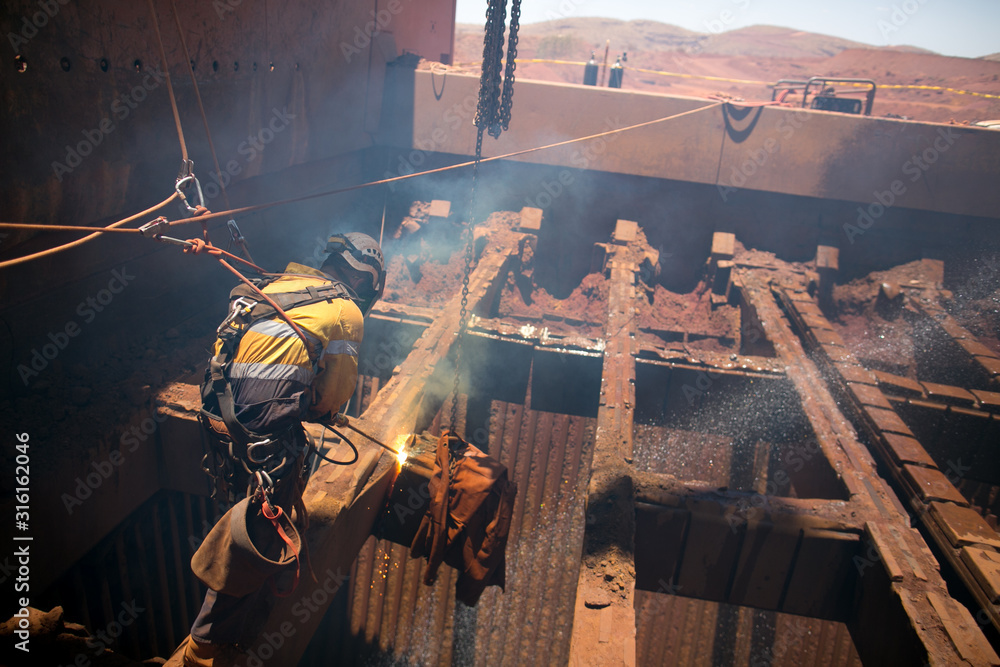 Rope access boilermaker abseiler wearing safety harness, helmet ...