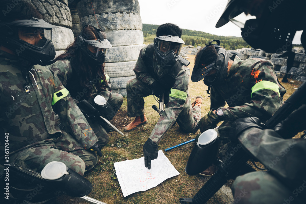 Paintballing team with map planning strategy Stock Photo | Adobe Stock