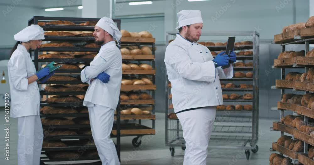 Main baker man using a new technology tablet to take photos of fresh ...