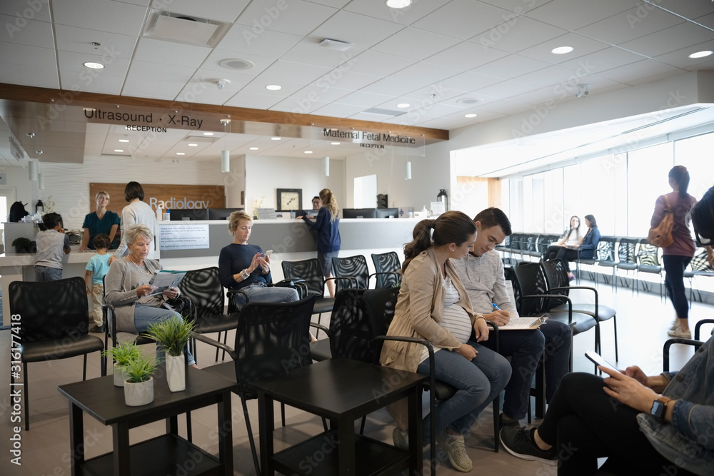 Pregnant couple filling out paperwork in clinic waiting room Stock ...