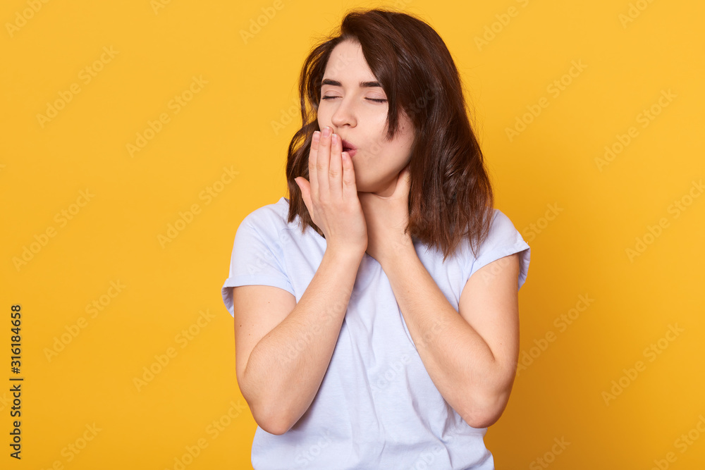 Portrait of tired girl with dark hair, standing and yawning with closed ...