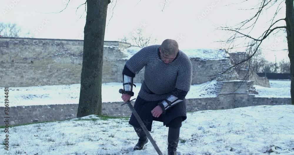 Strong soldier in armor with sword kneels on winter nature Stock Video ...