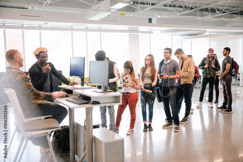 Students queue at information desk in university library Stock Photo ...