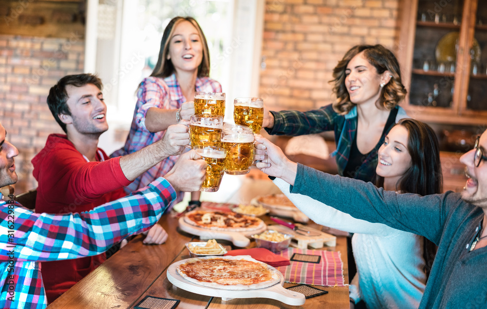 Friends group drinking beer and eating pizza at bar restaurant ...