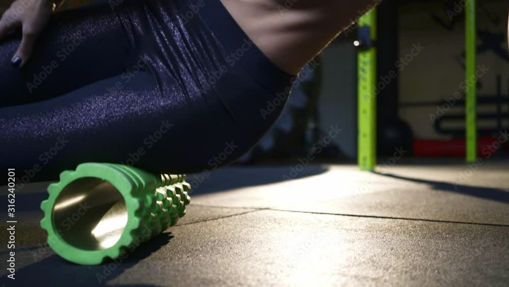 Young girl doing restorative exercise with a bolster on floor of gym ...