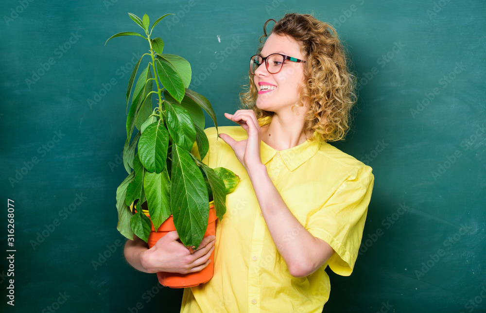 taking care of flowers. happy student girl with plant at blackboard ...