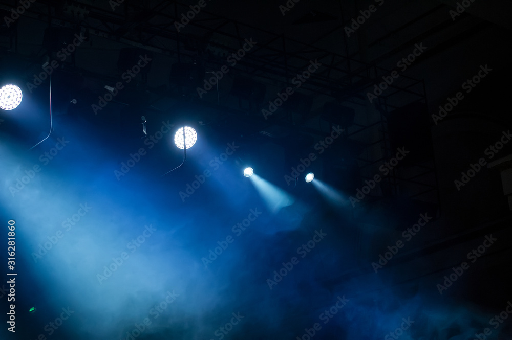 Rays of spotlights illuminate the concert stage with blue light against ...