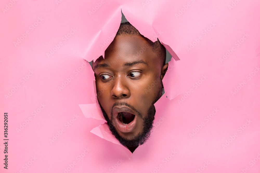 handsome young black man with head through a cardboard paper surprised ...