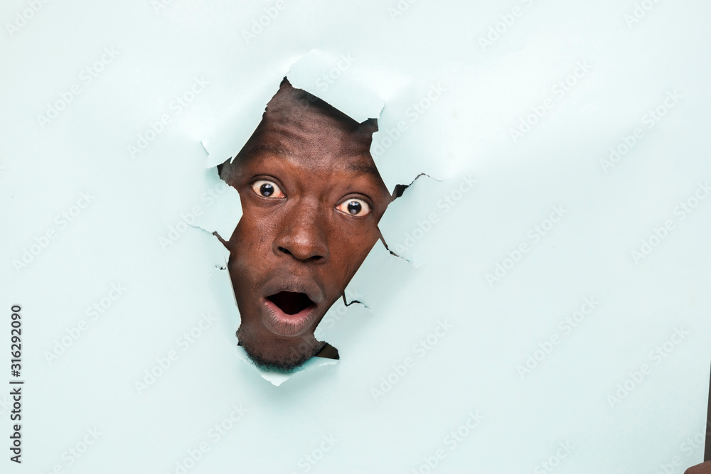 handsome young black man with head through a cardboard paper looking ...