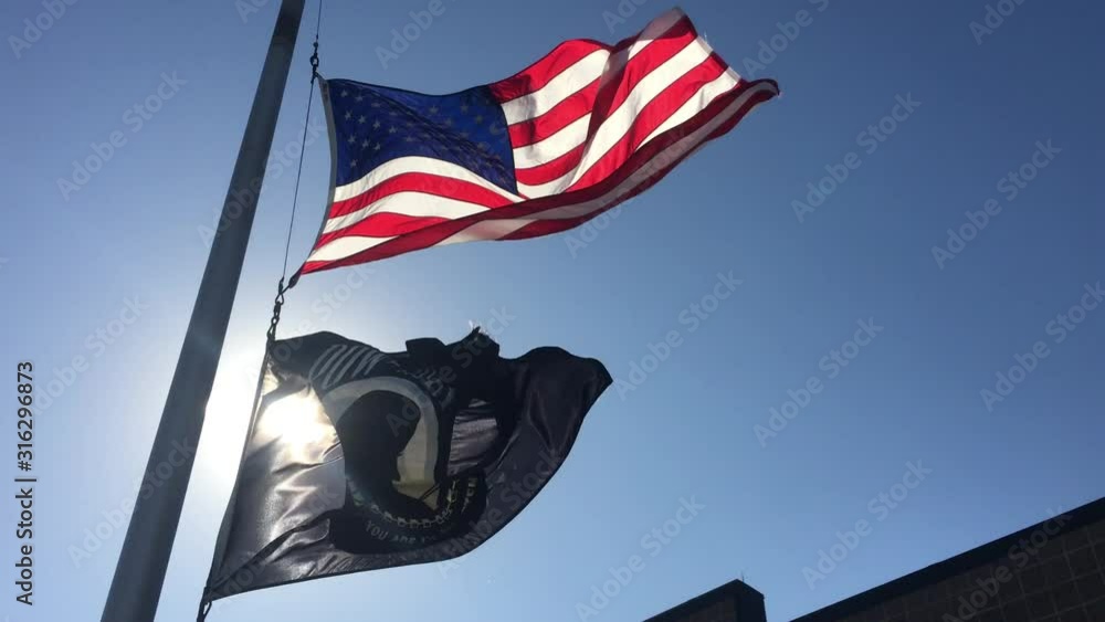 POW MIA flag flying along with American flag with sunlight illuminating ...