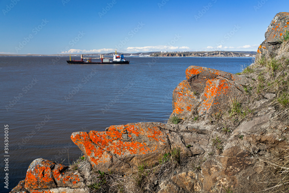 Landscape with a cargo ship in the water area of the Anadyr estuary. In ...