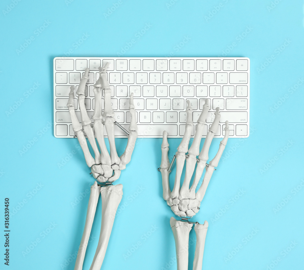 Human skeleton using computer keyboard on light blue background, top ...
