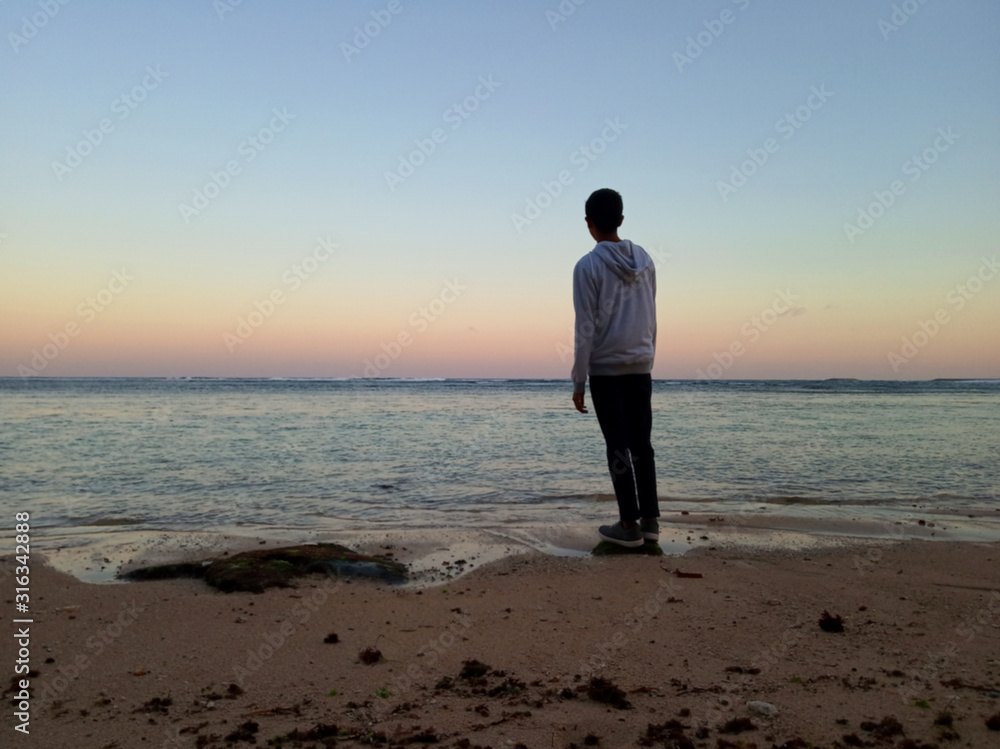 Blurry image of young man standing alone in the beach, looking at the ...