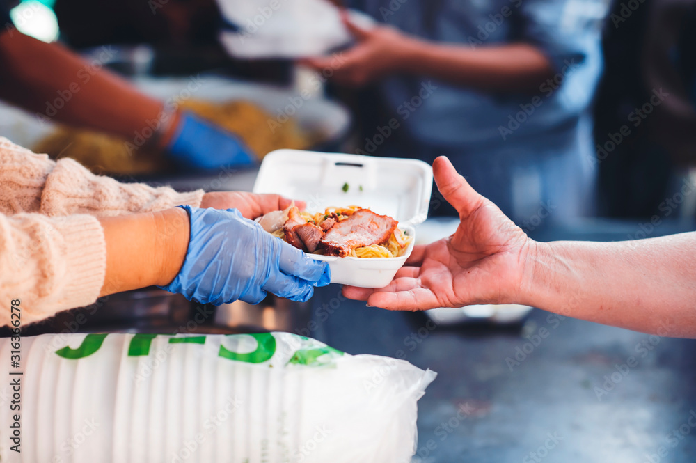 The hands of the poor handed a plate to receive food from volunteers to ...