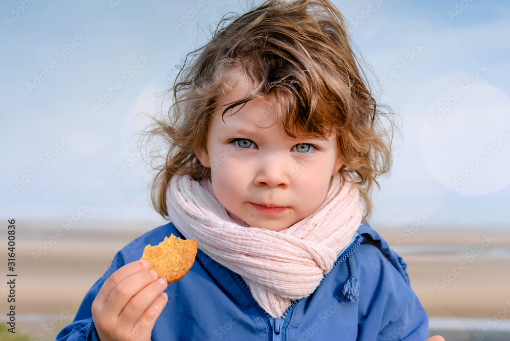 cute little girl eating a cookie outside Stock Photo | Adobe Stock