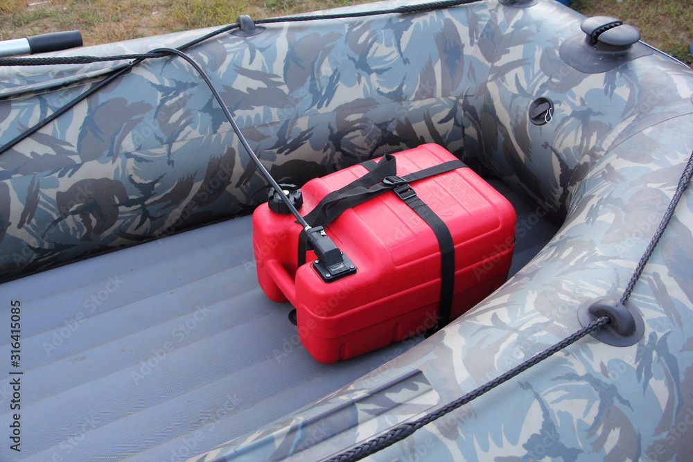Red plastic fuel tank in bow cockpit of camouflage inflatable motor ...